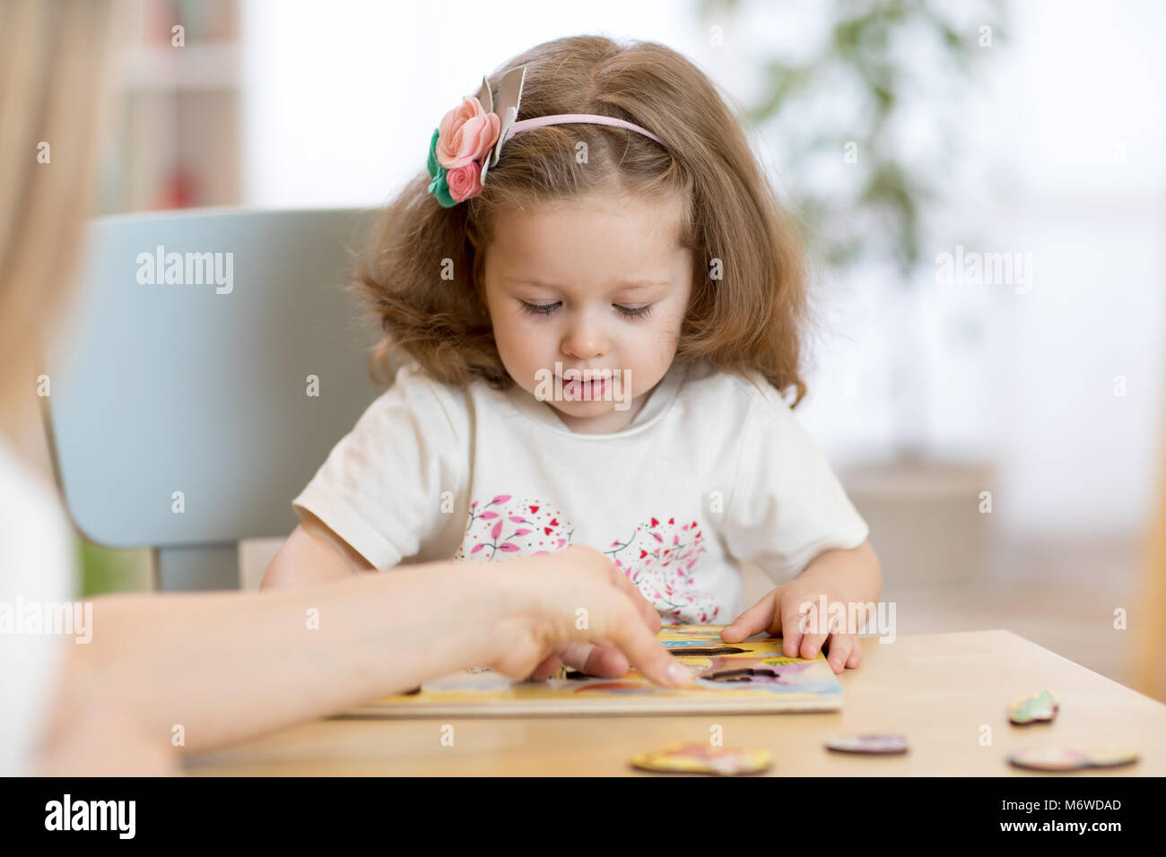 Child kid girl playing with puzzle shapes on low table in children room ...