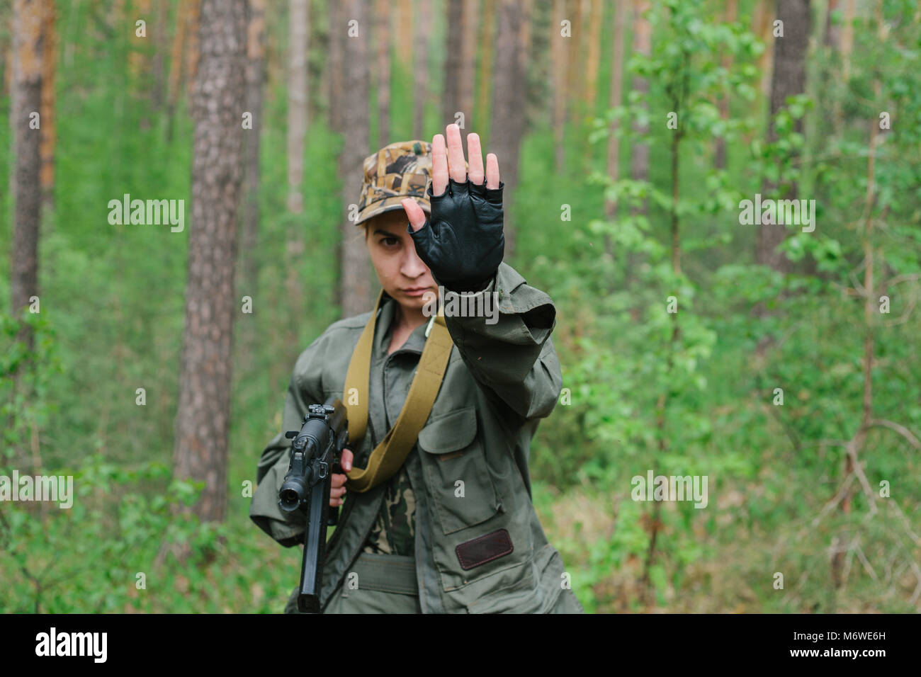 A woman soldier with a weapon shows a hand stop Stock Photo - Alamy