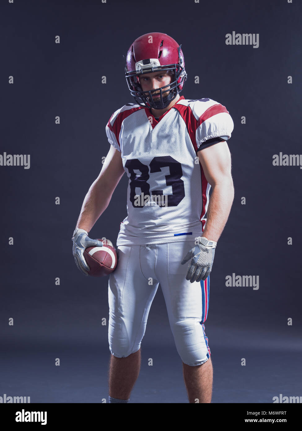 Portrait of a strong muscular American Football Player isolated on gray ...