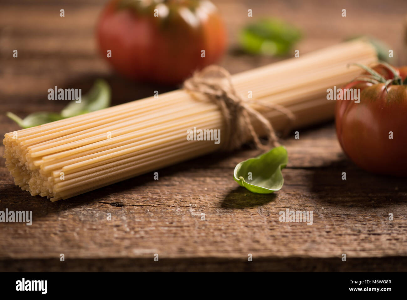 Spaghetti and tomatoes with herbs on an old and vintage wooden table ...