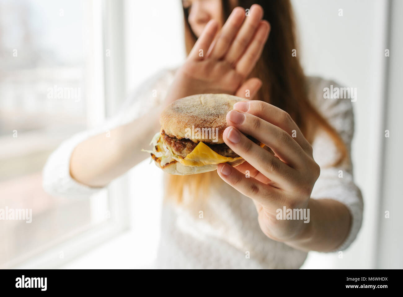 A young girl shows a sign by hand signifying there is no burger ...