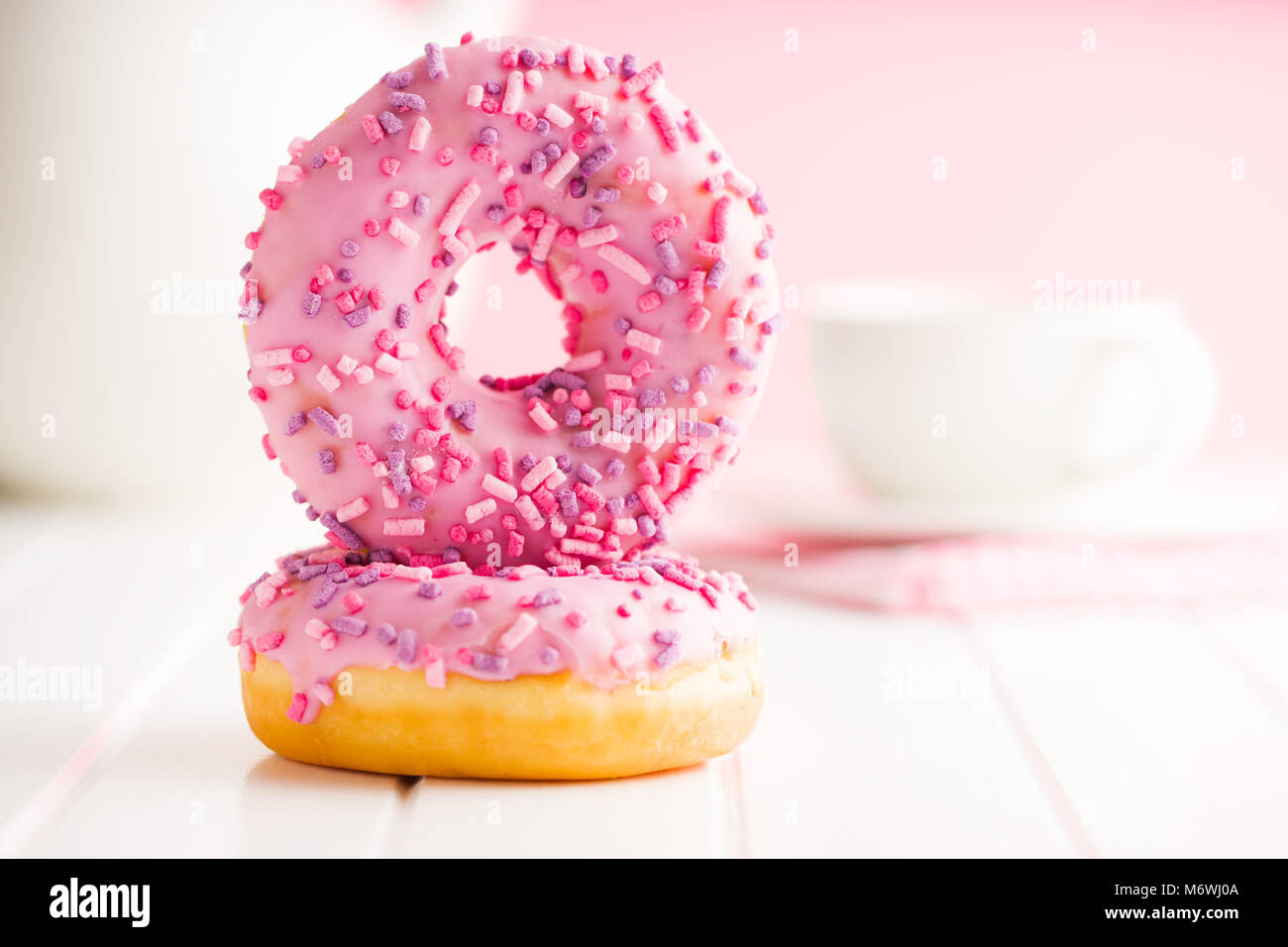 Two pink donuts on white table Stock Photo - Alamy