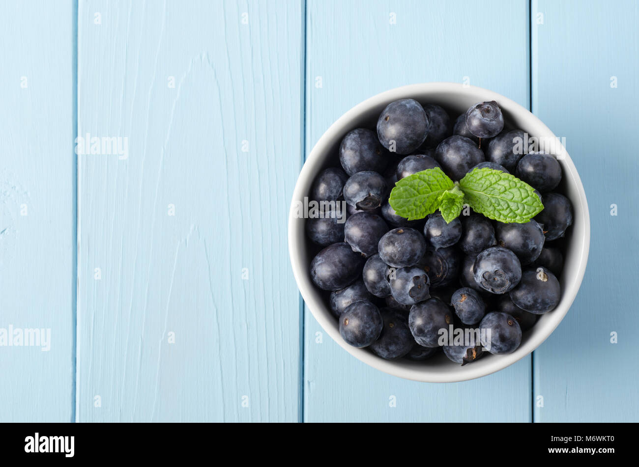 Overhead shot of fresh blueberries piled into a white bowl with a fresh ...