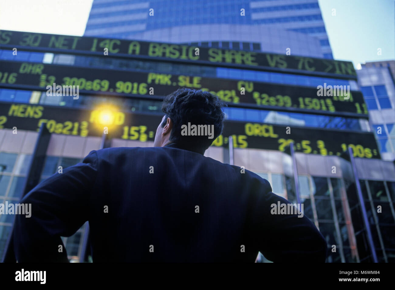 1998 HISTORICAL CAUCASIAN BUSINESS MAN STANDING LOOKING UP AT STOCK ...