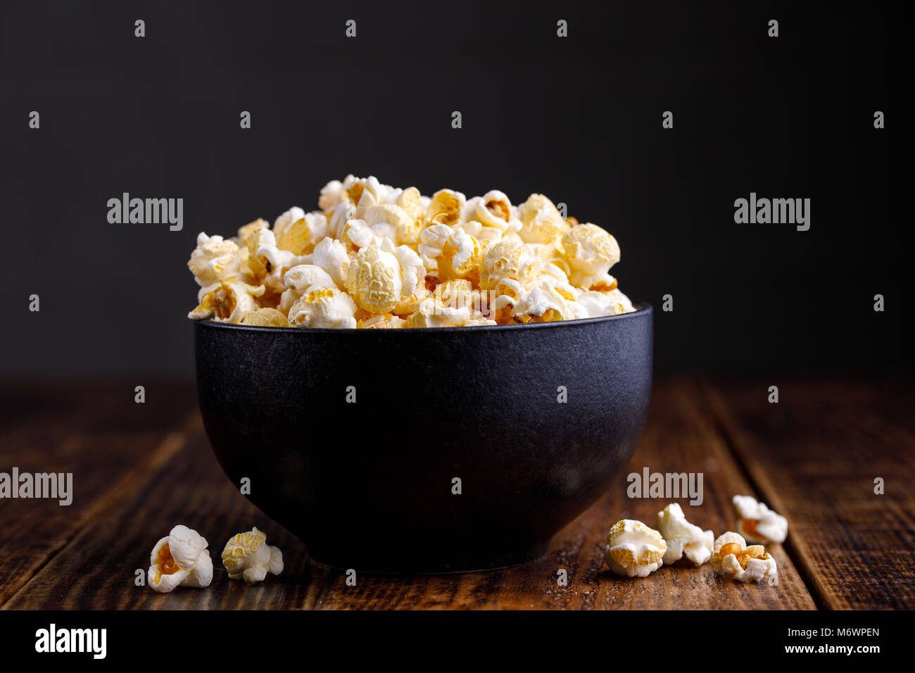 Popcorn in a refined ceramic bowl and scattered near her. A still life ...