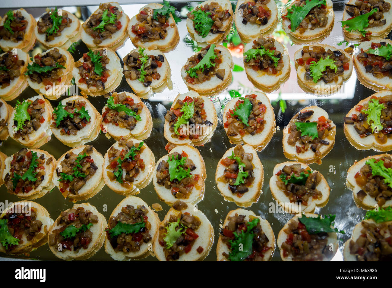 canape set with white bread and vegetable topping arranged in rows on ...