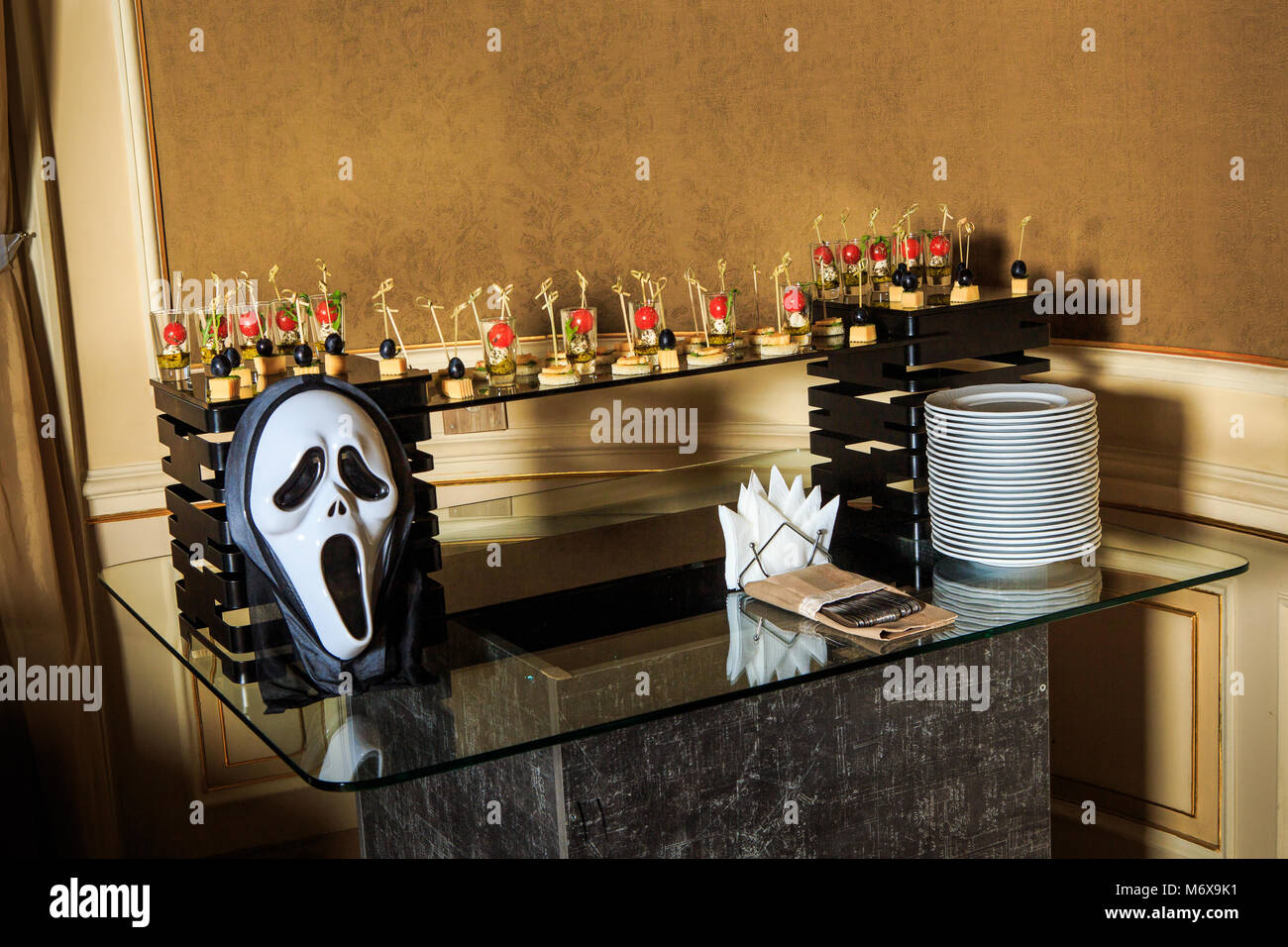 cheese snack, plates, cutlery, scary mask arranged on glass table on ...