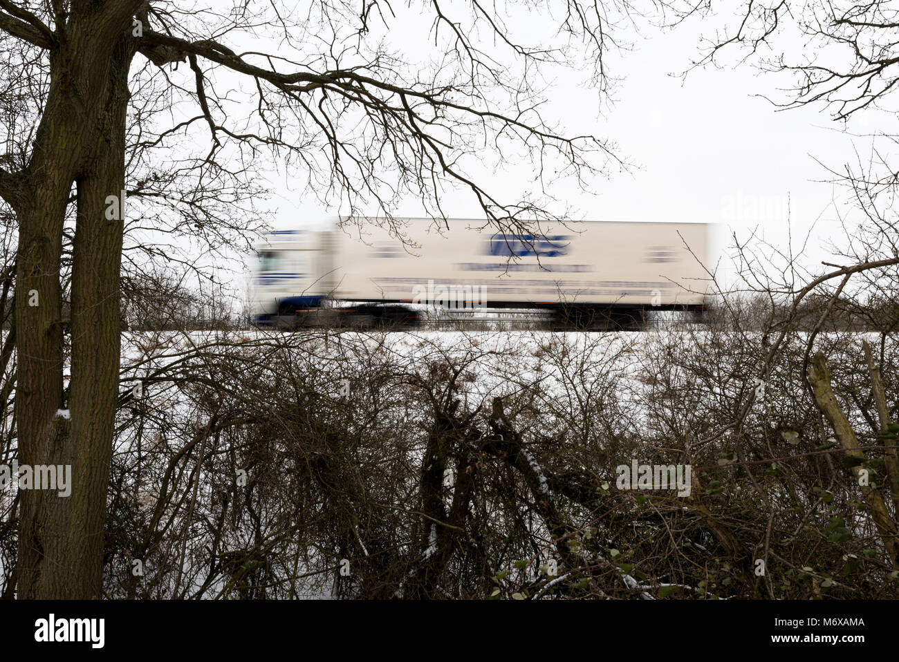A heavy haulage artic lorry passes by in a motion blur along a main ...