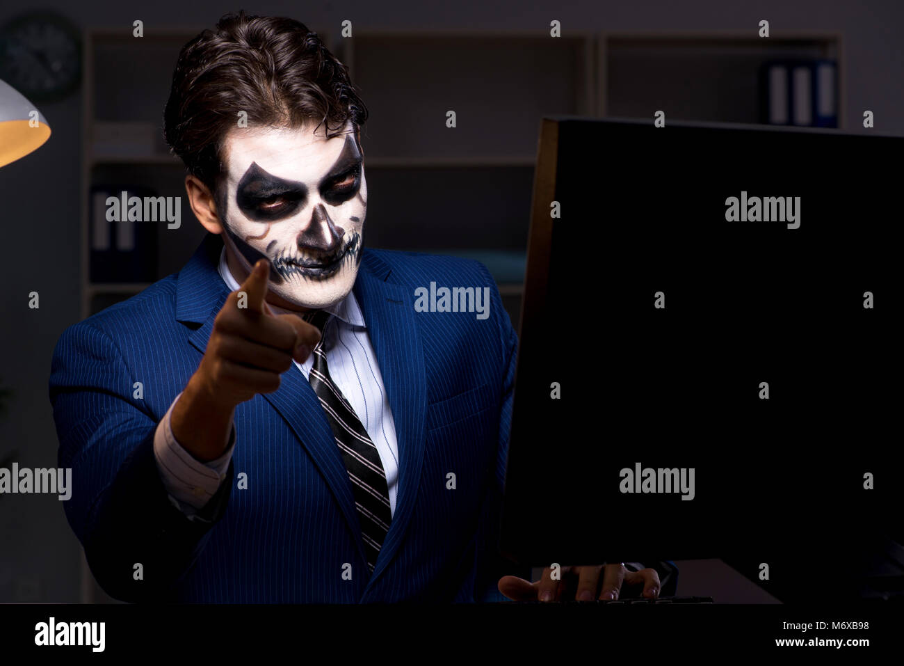 Businessman with scary face mask working late in office Stock Photo - Alamy