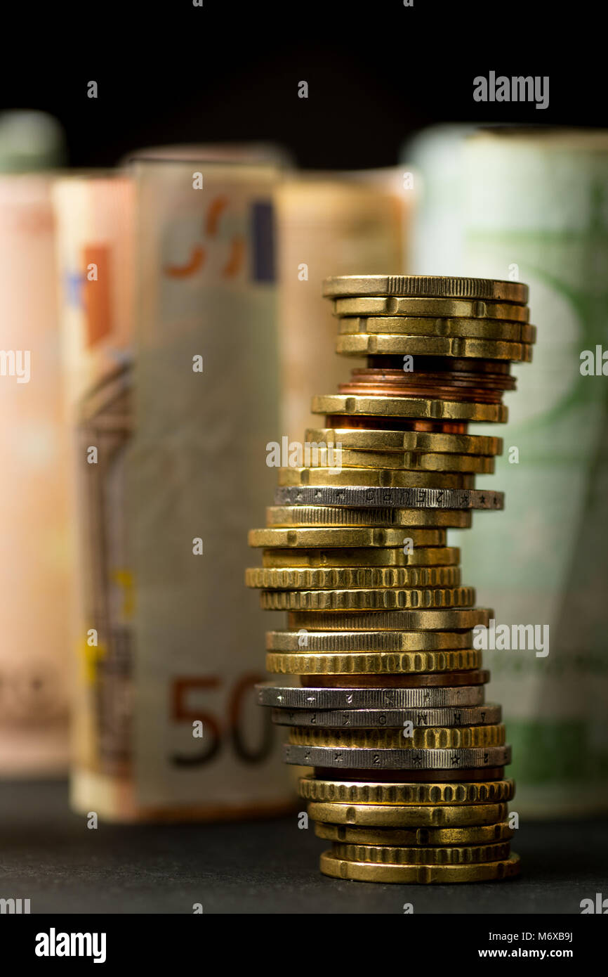 Stack of euro coins and rolls of bank notes in the background Stock ...