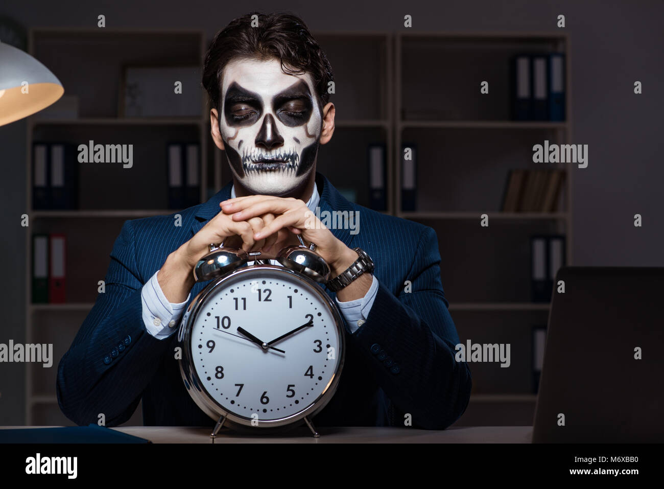 Businessman with scary face mask working late in office Stock Photo - Alamy