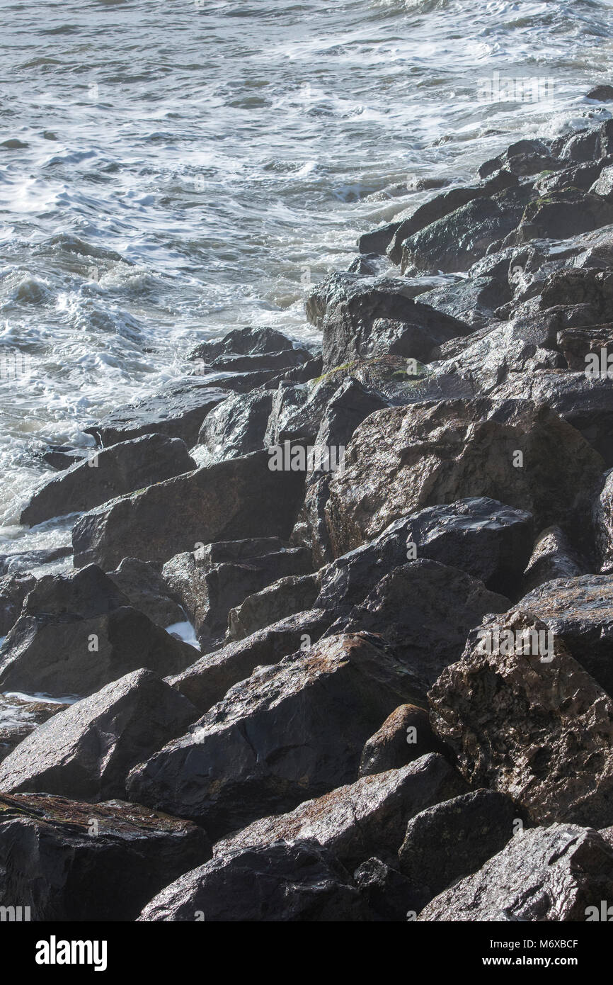 a rocky seashore on the seafront with rocks and waves crashing onto the ...