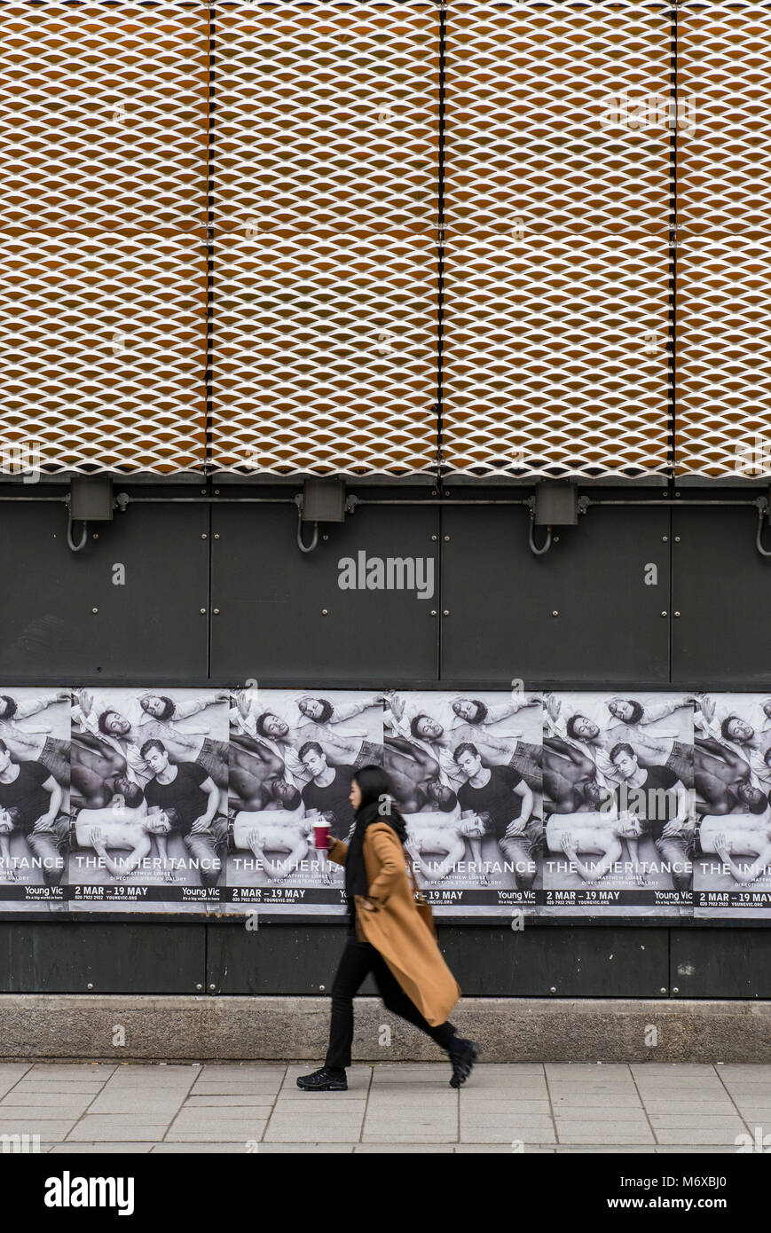 a young woman walking along a london street alone past advertising ...