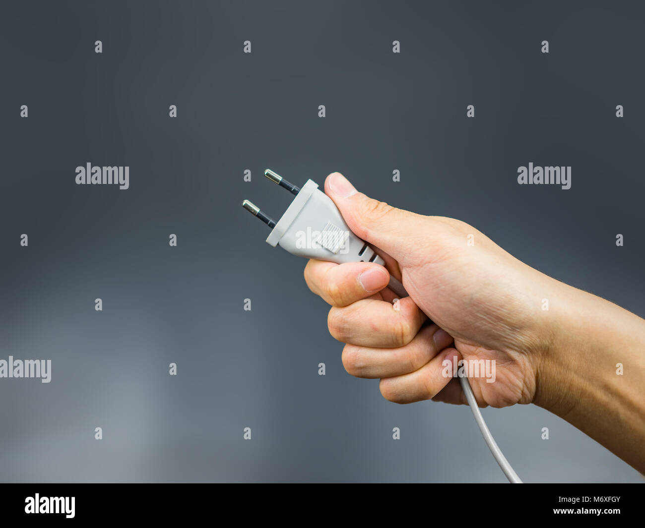 Plug hand holding on black background Stock Photo - Alamy