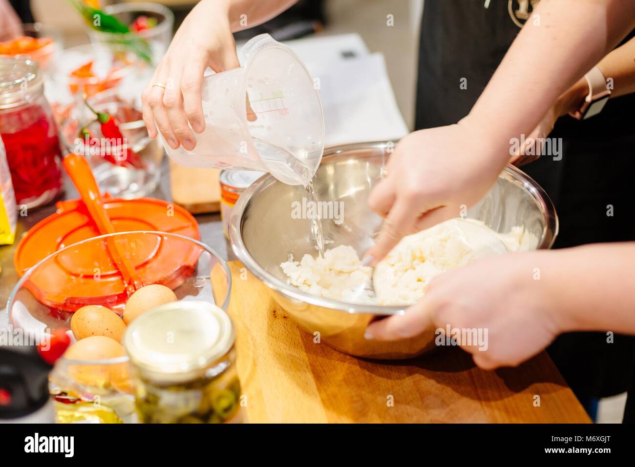 Woman cook preparing dough in bowl and adding water Stock Photo - Alamy