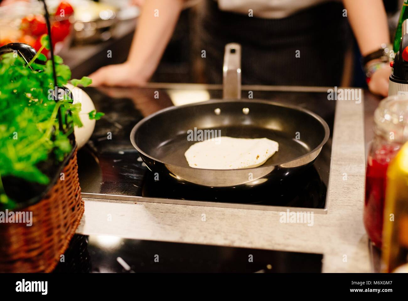 Woman frying tortilla wraps on frying pan in the kitchen Stock Photo ...