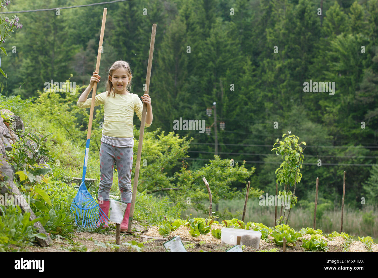Little girl holding gardening tools, having fun in the garden, planting ...