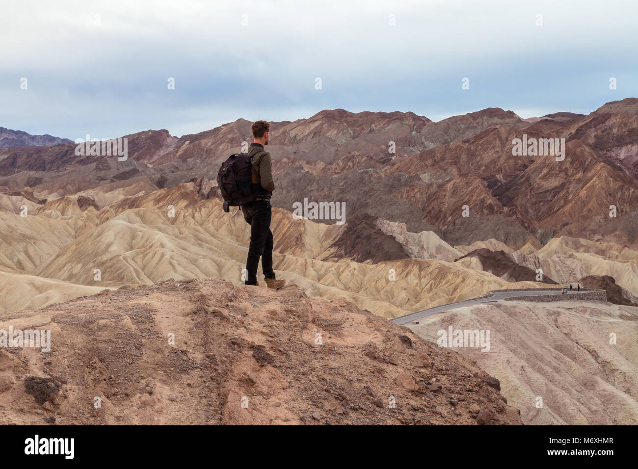 Hiker stood on the mountain cliff looking down at the view point at ...