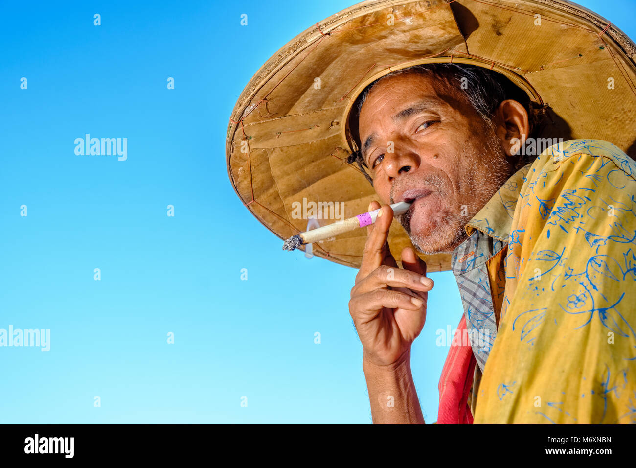 Portrait of a bicycle riksha driver, smoking a Cheerot, a local cigar ...