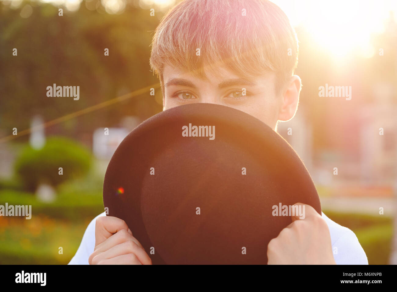 Beautiful woman hiding face behind hat showing eyes Stock Photo - Alamy