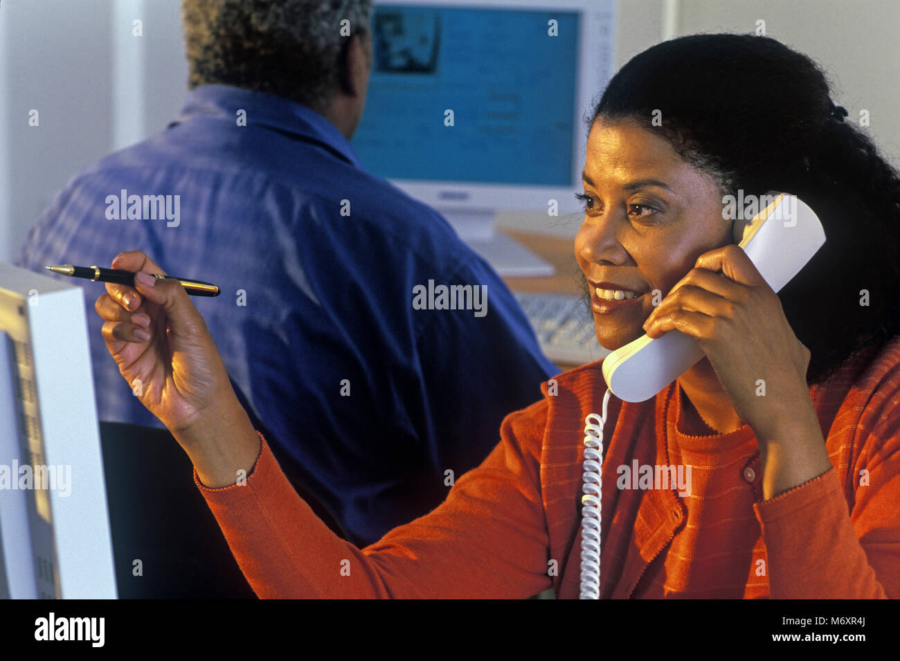 2000 HISTORICAL OFFICE WORKERS HOLDING LANDLINE TELEPHONE SITTING AT ...