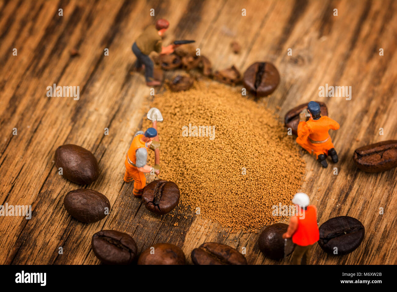 Miniature figures working on instant coffee macro photography on wood ...