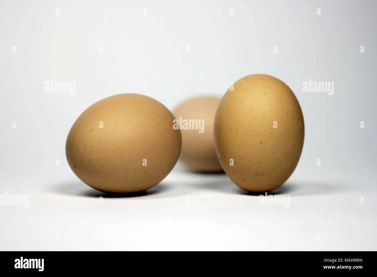 Three eggs are arranged two layers and one stand, white background ...
