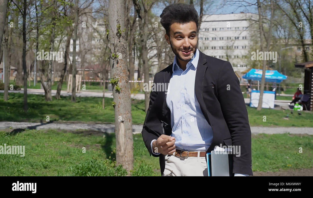 Modern student walking in park with laptop in hand Stock Photo - Alamy