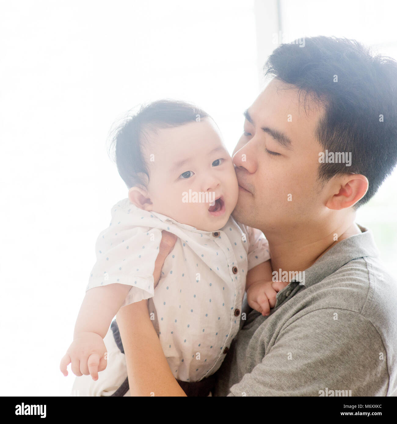 Happy Asian family at home. Father kissing baby boy, living lifestyle ...