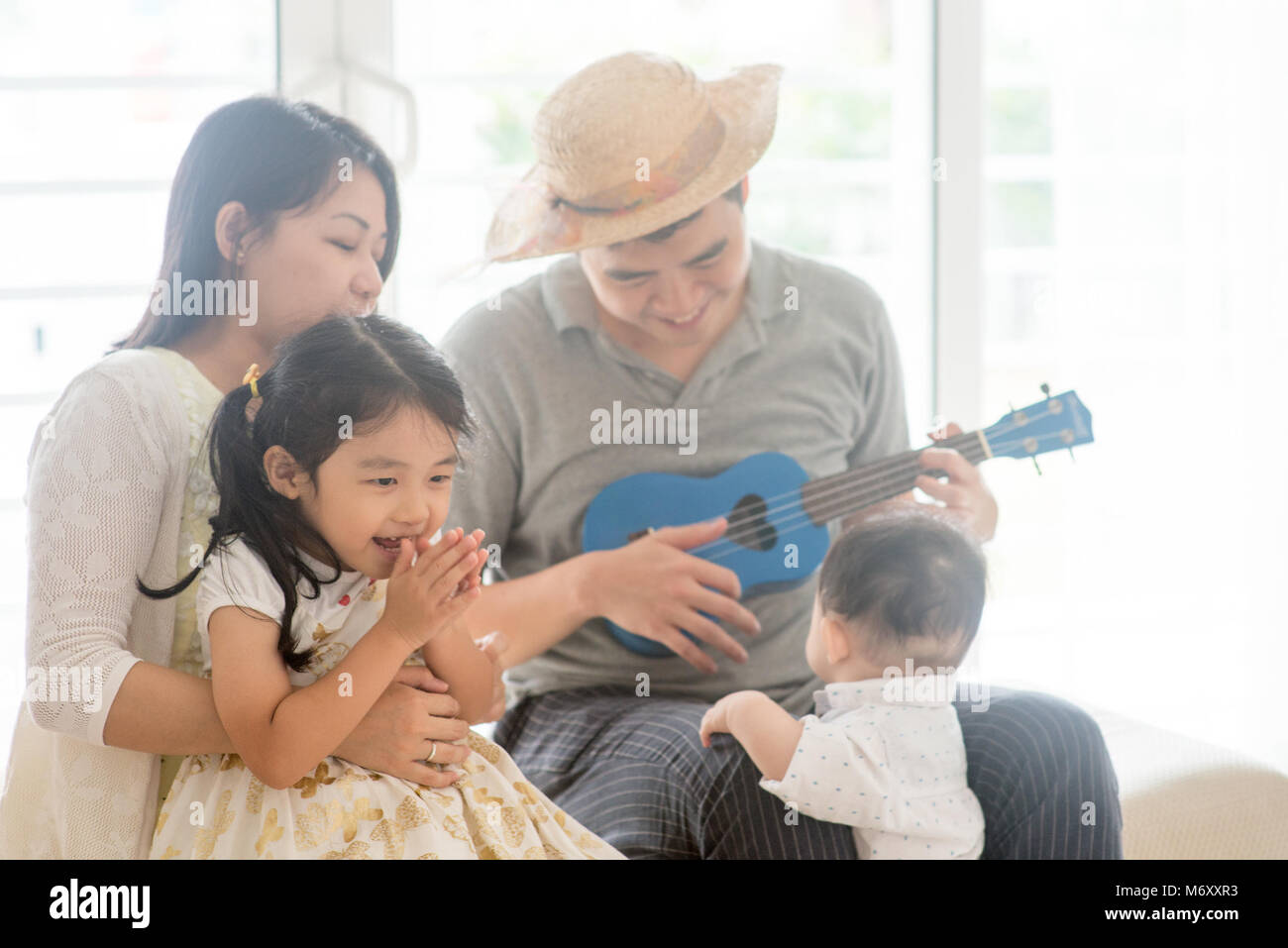Parents and children singing and playing ukulele together. Asian family ...