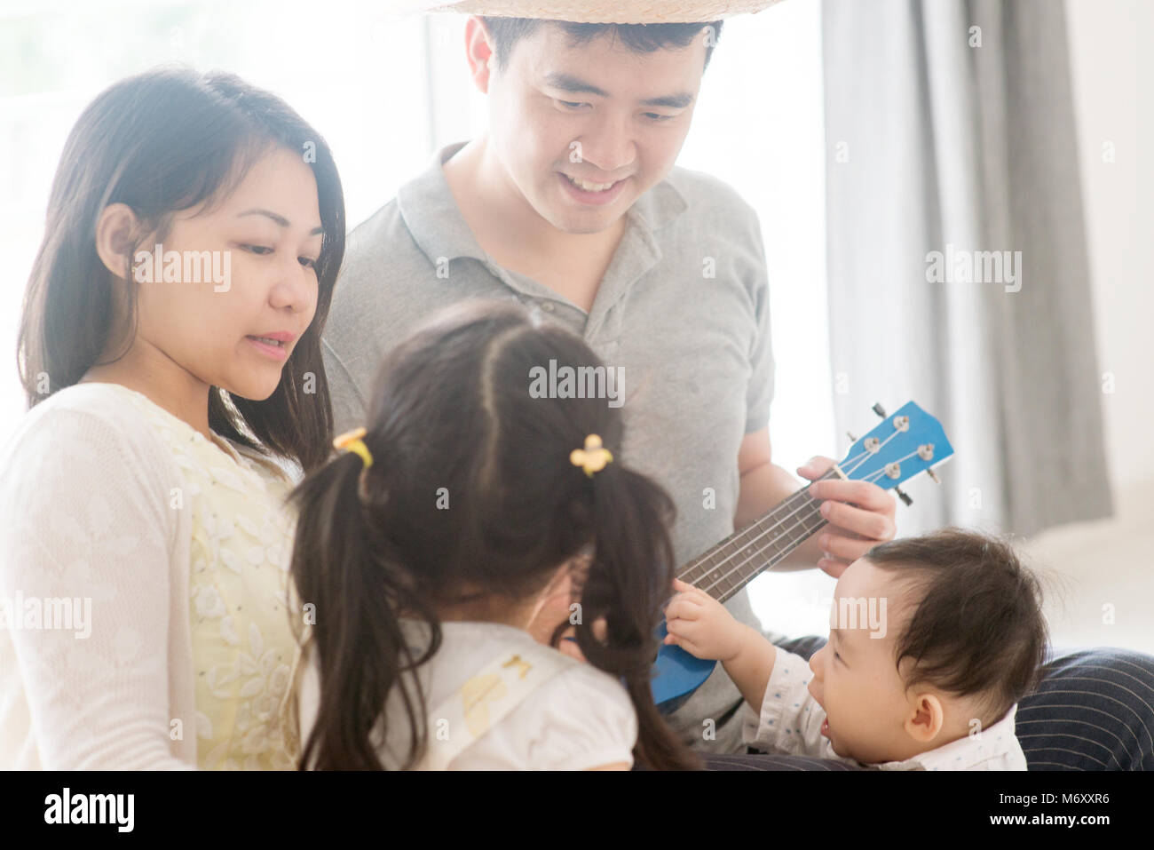 Parents and children singing and playing ukulele together. Asian family ...