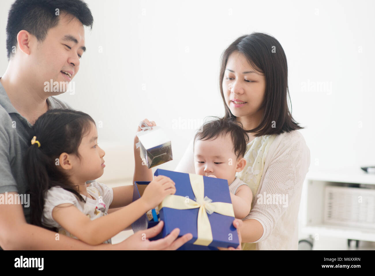 Parents and children open present box together. Asian family spending ...