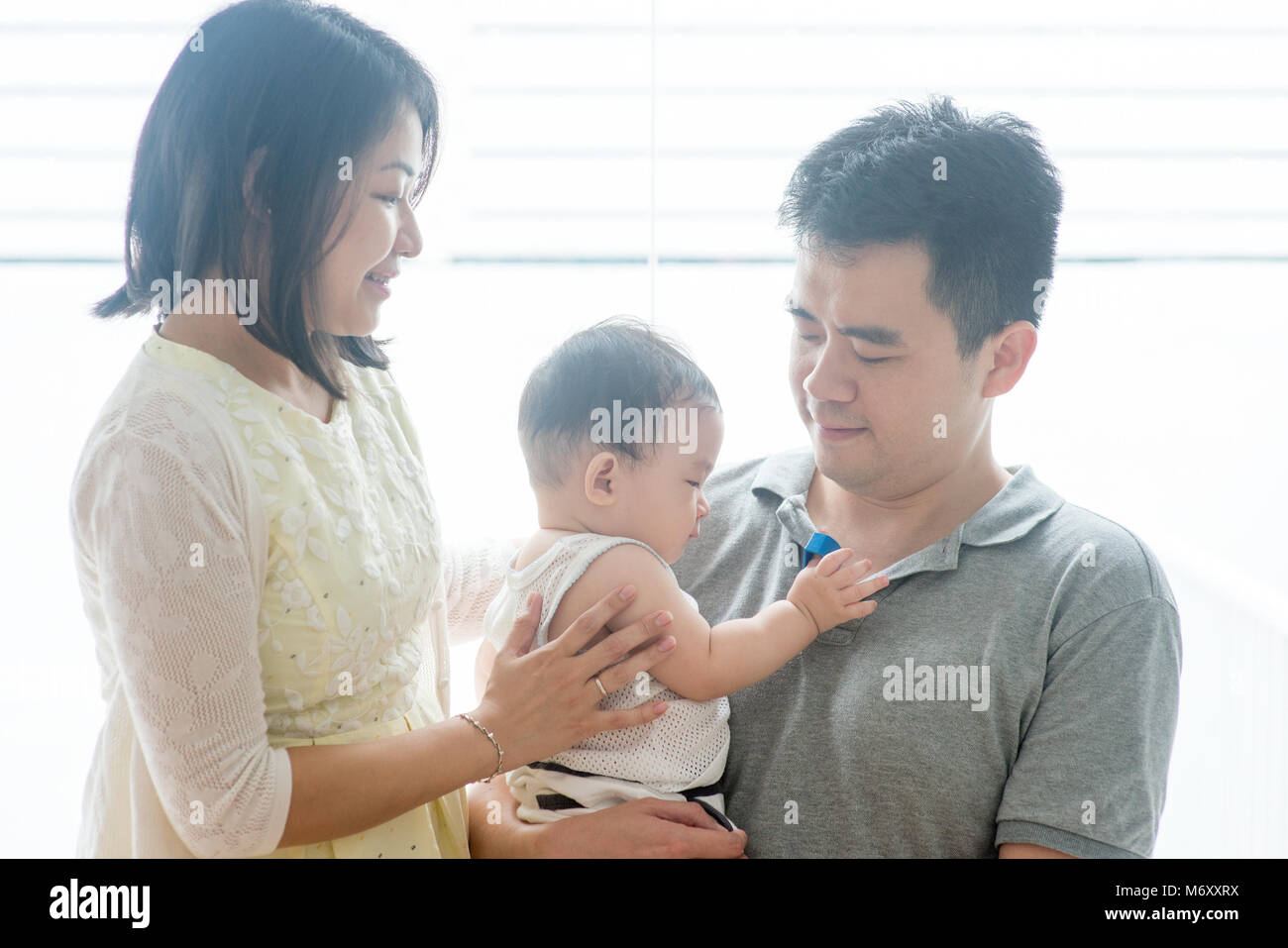 Parents and baby. Happy Asian family spending quality time at home ...
