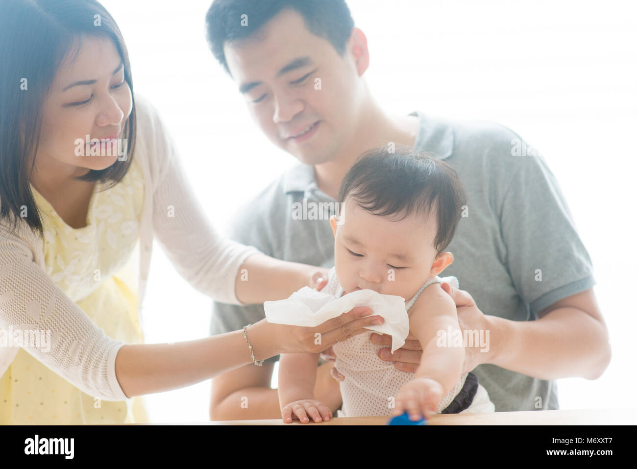 Mother blow baby nose with tissue paper. Asian family spending quality ...