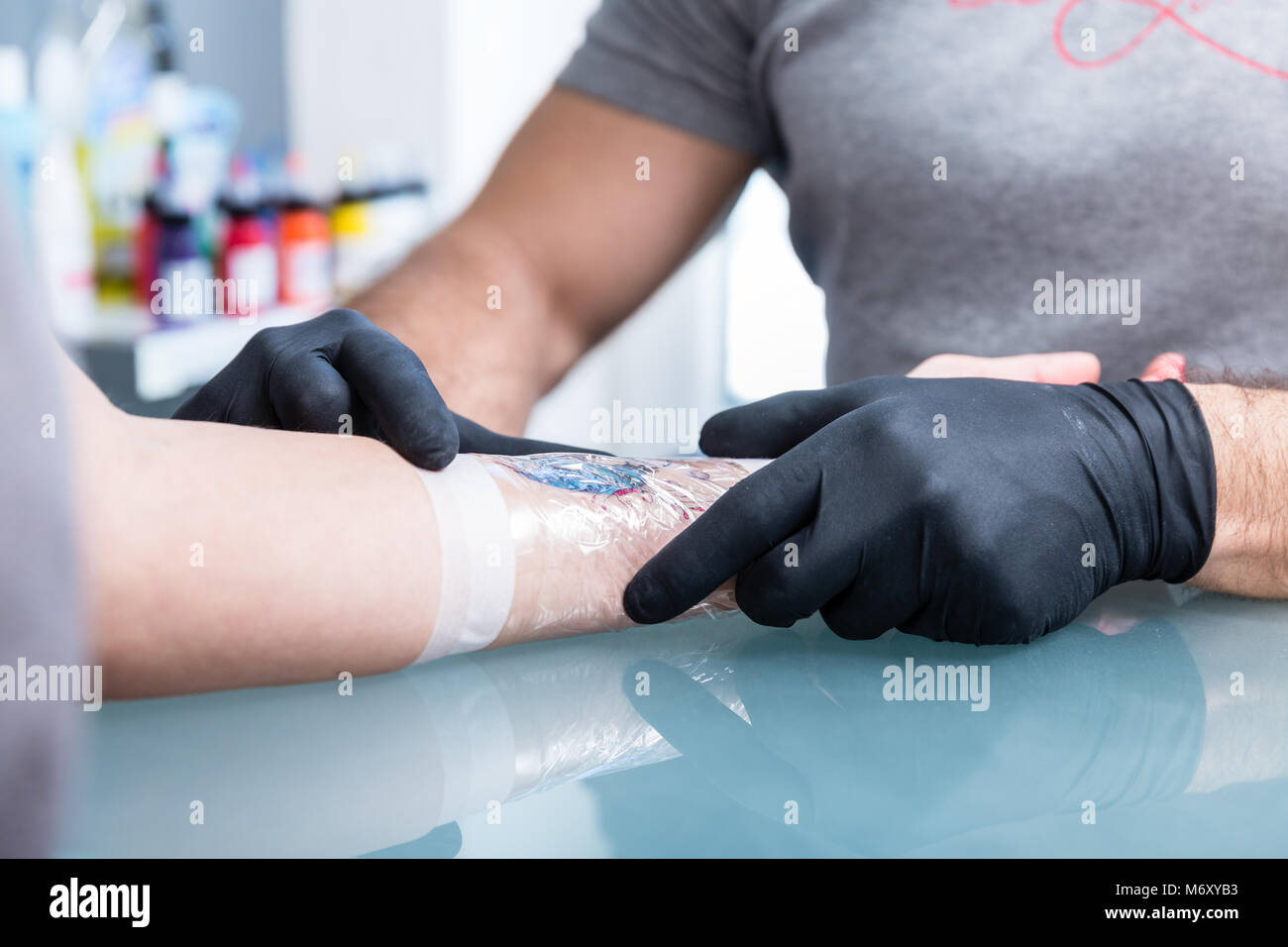 Close-up of the hand of a tattoo artist shading a colorful butterfly ...