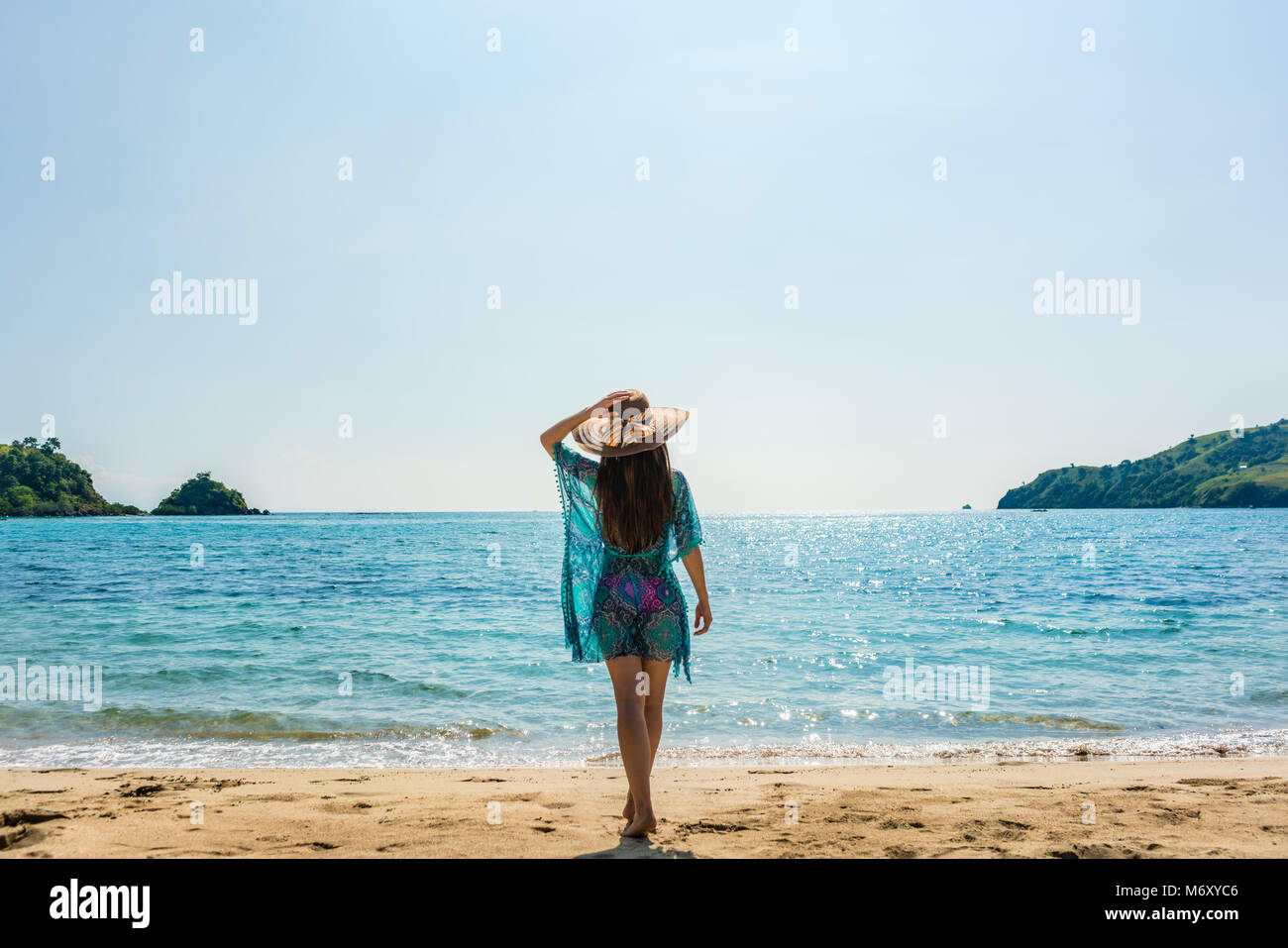 Young fit woman standing on a tropical beach in the summer vacation ...