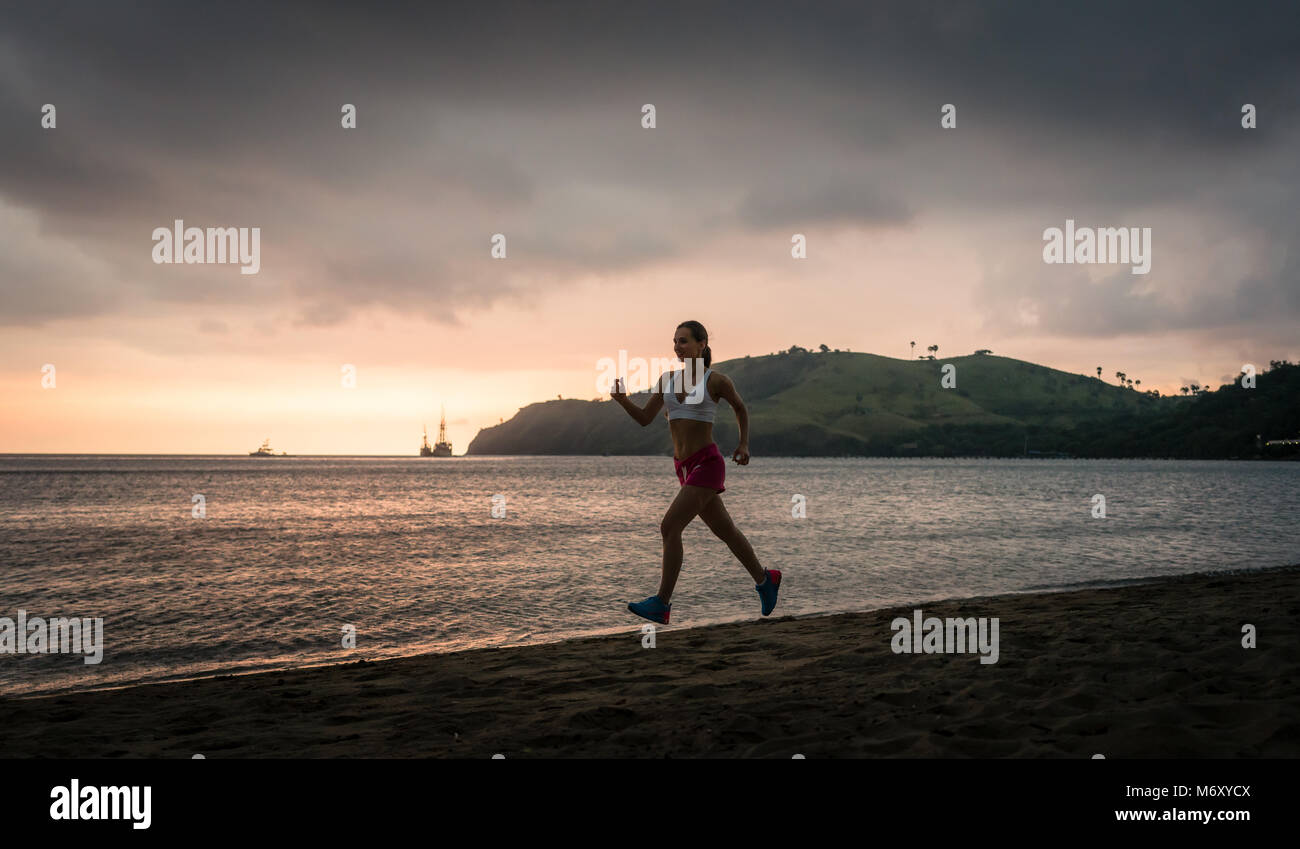 Fit young woman running on the beach during summer vacation in Flores ...