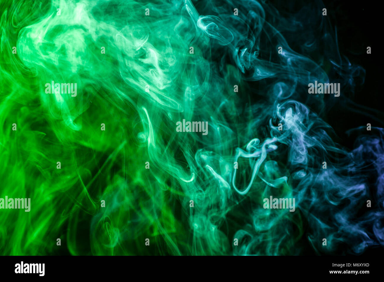 Dense multicolored smoke of blue and green colors on a black isolated ...