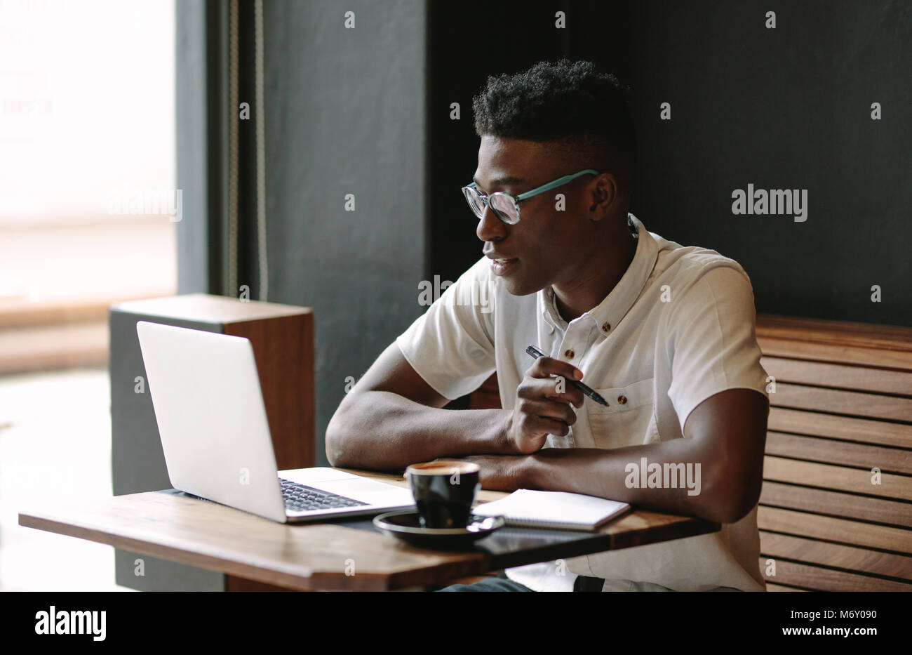Man working on his laptop computer at a coffee shop. Freelancer making ...
