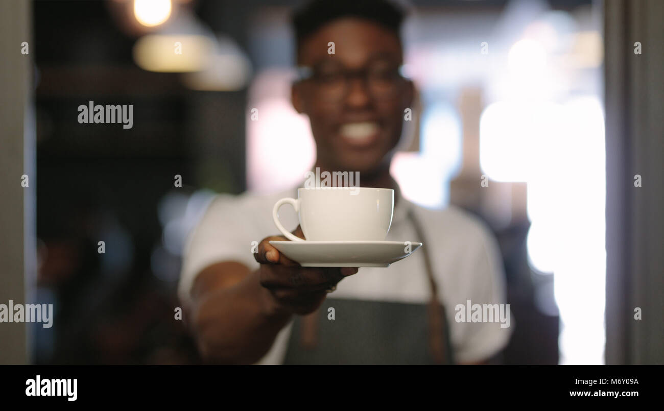 Closeup of barista offering a coffee cup. Coffee shop owner serving ...