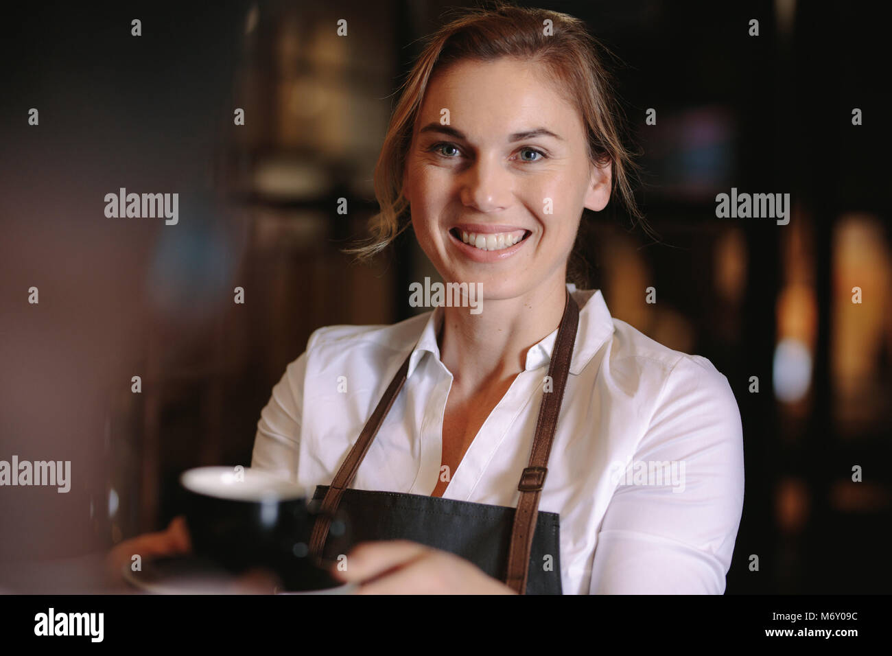 Smiling woman serving coffee inside a coffee shop. Happy coffee shop ...