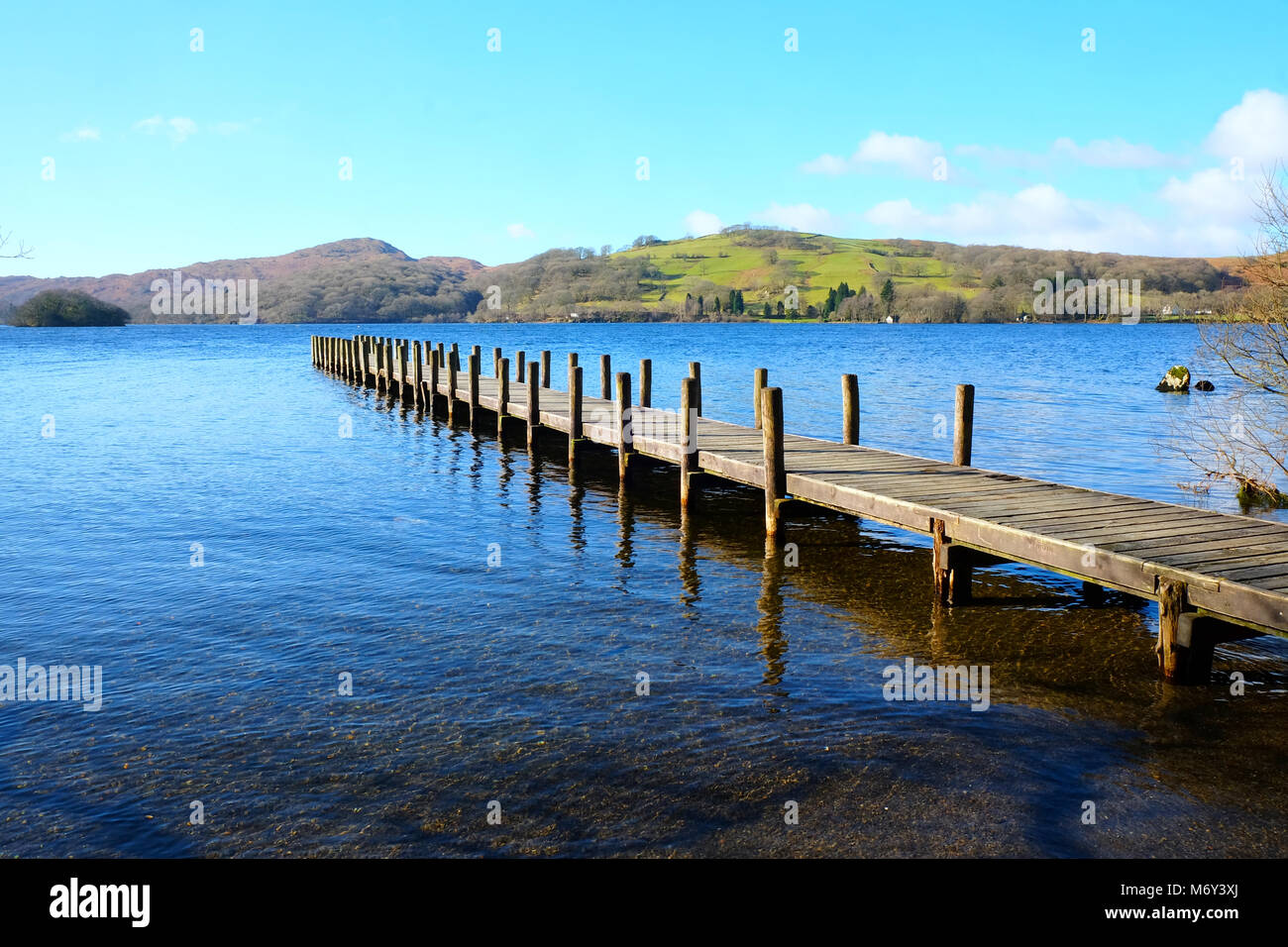 Long straight symetrical wooden foot jetty jutting out over a calm blue ...