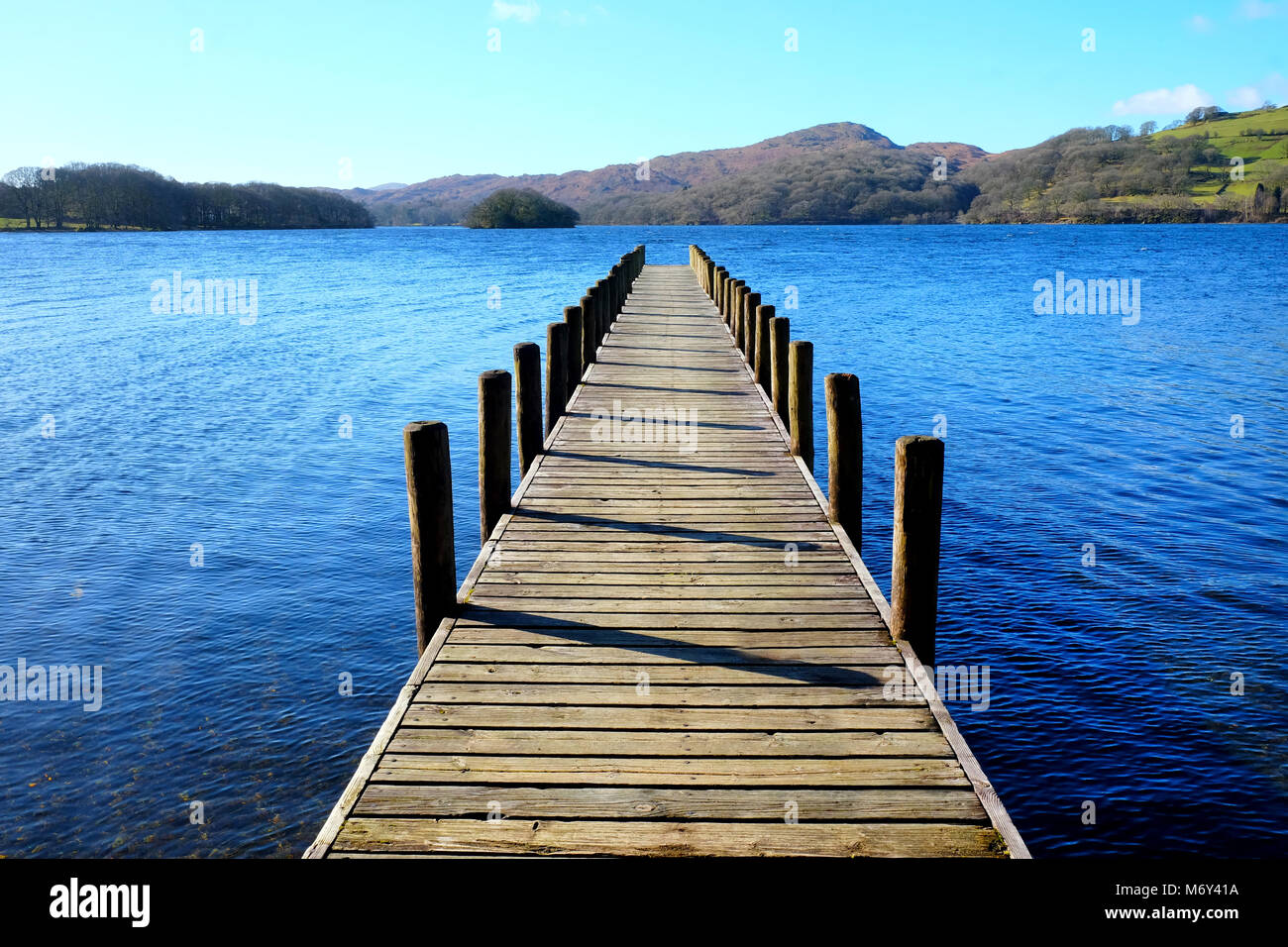 Long straight symetrical wooden foot jetty jutting out over a calm blue ...