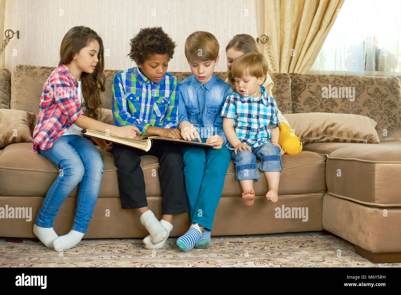 Kids reading a book indoors Stock Photo - Alamy