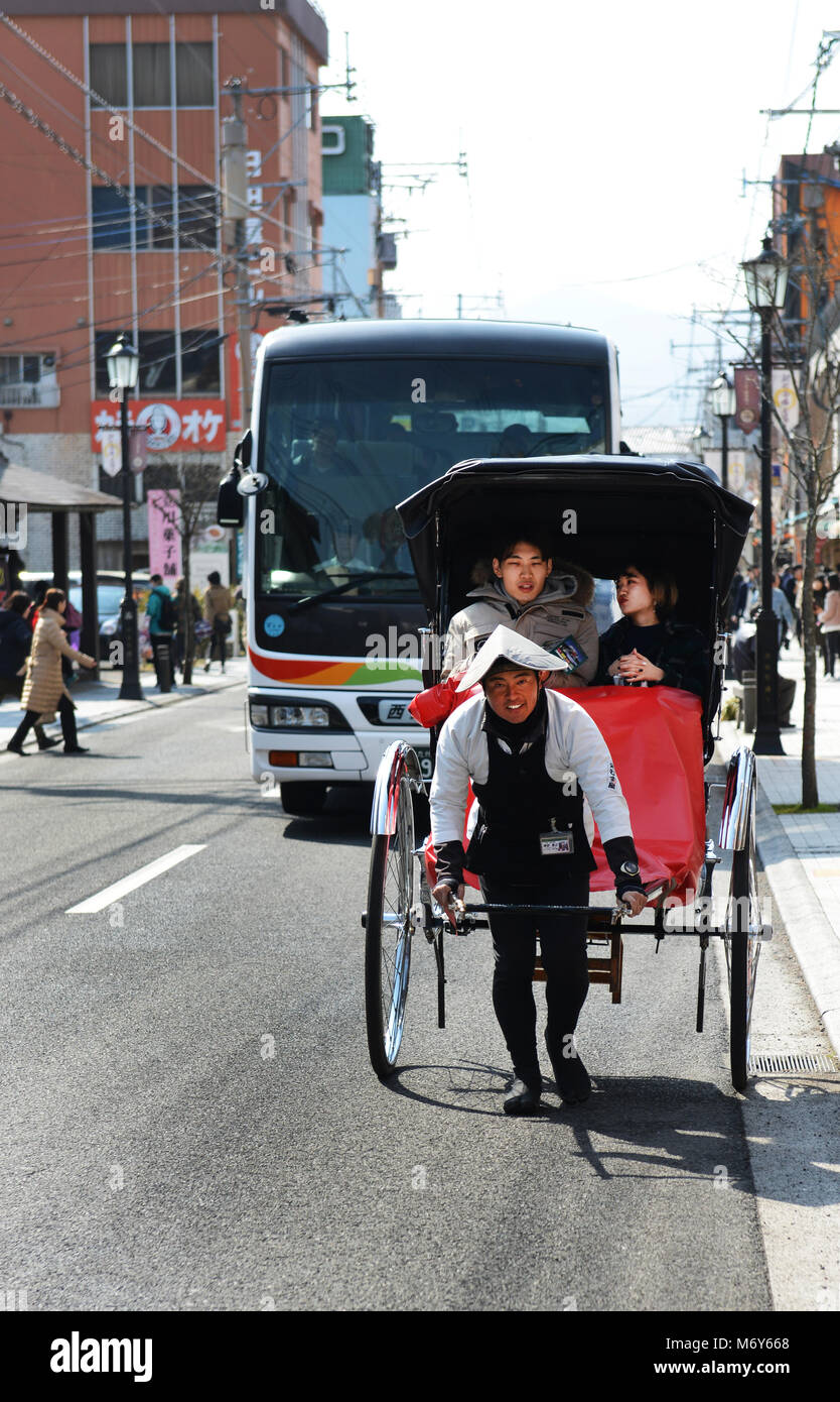 Pulling a hand pulled rickshaw with tourist through the Yufu town ...