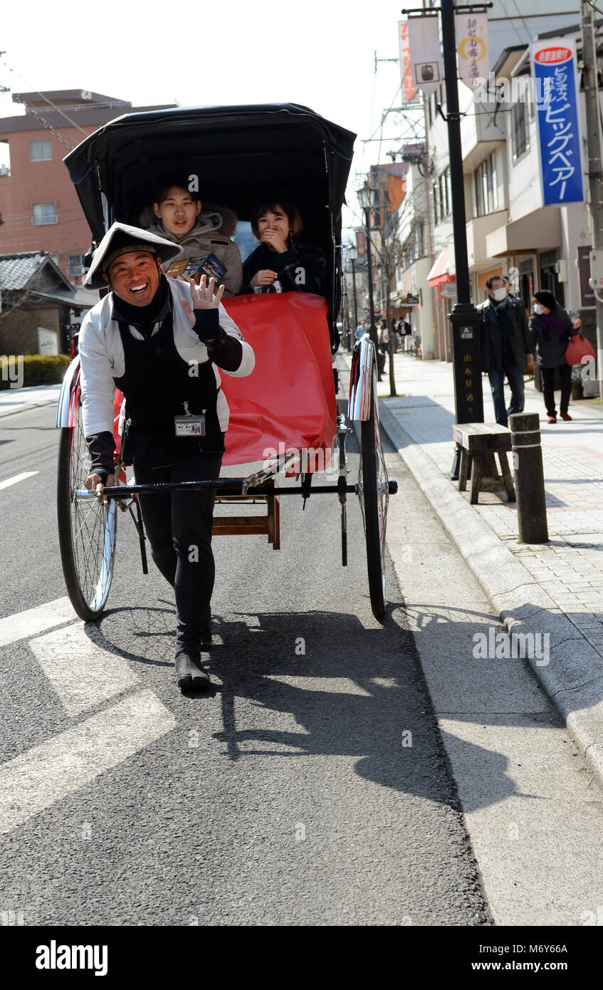 Pulling a hand pulled rickshaw with tourist through the Yufu town ...