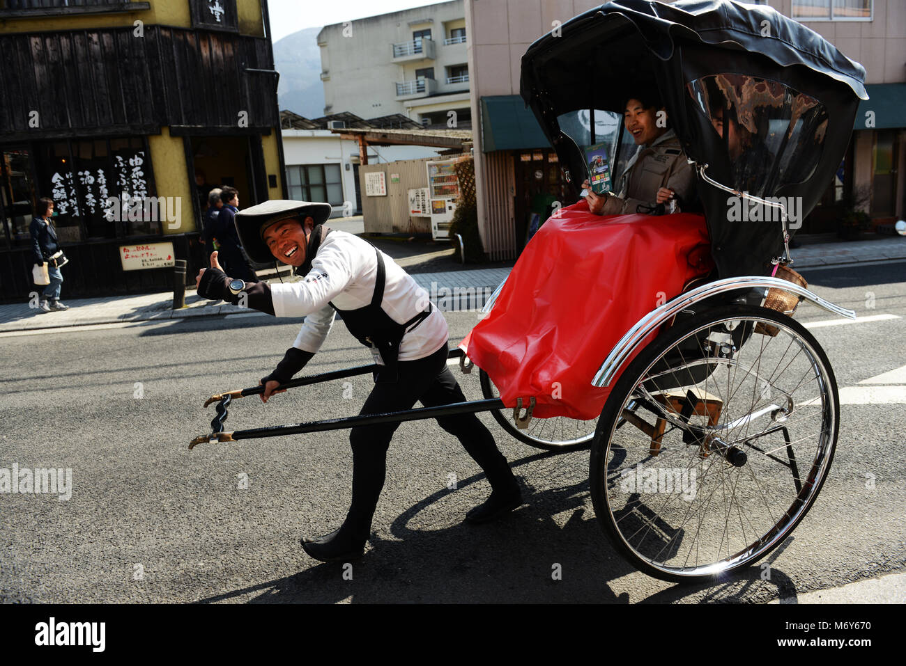 Pulling a hand pulled rickshaw with tourist through the Yufu town ...