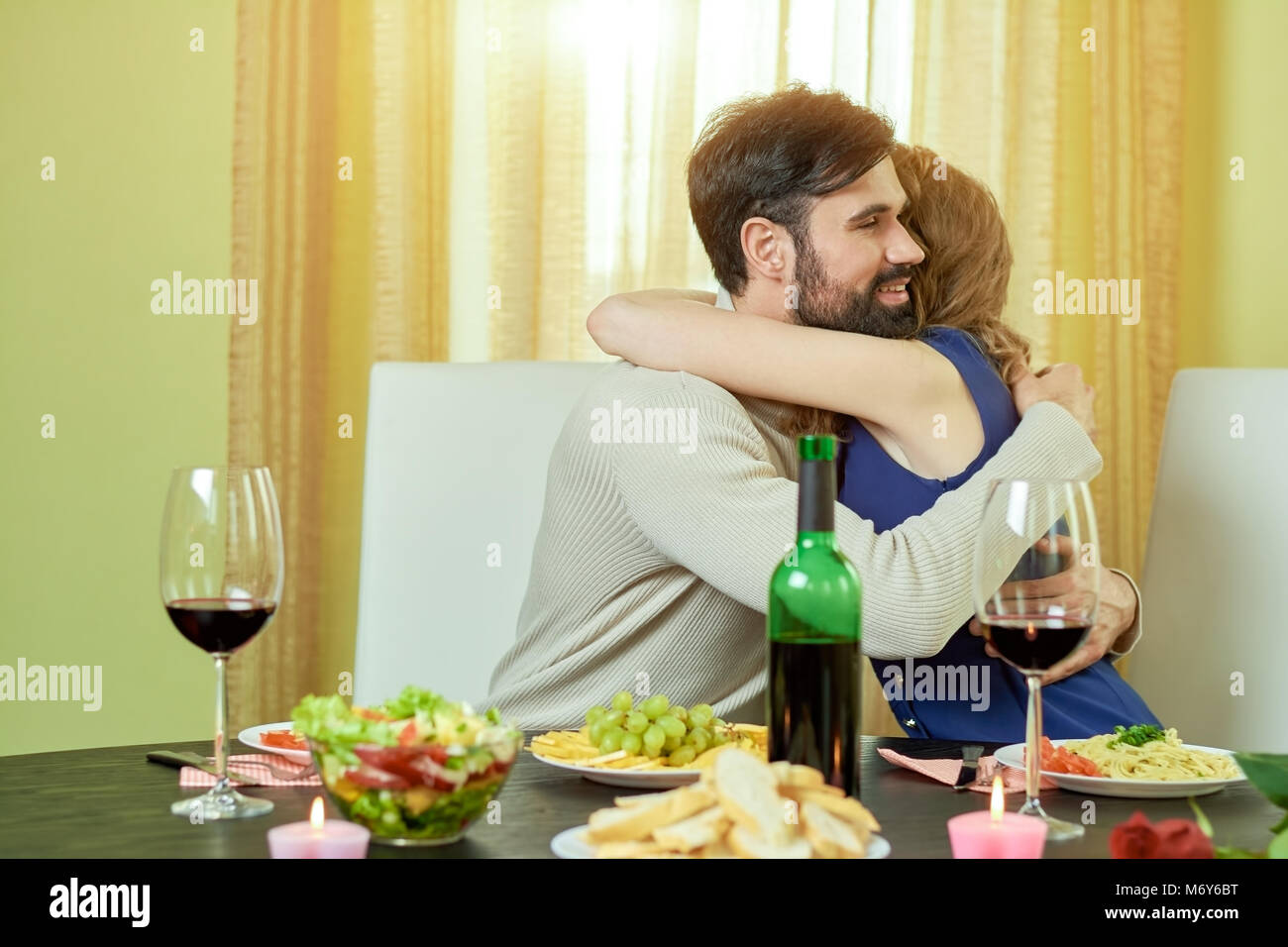 Couple at dinner table hugging Stock Photo - Alamy