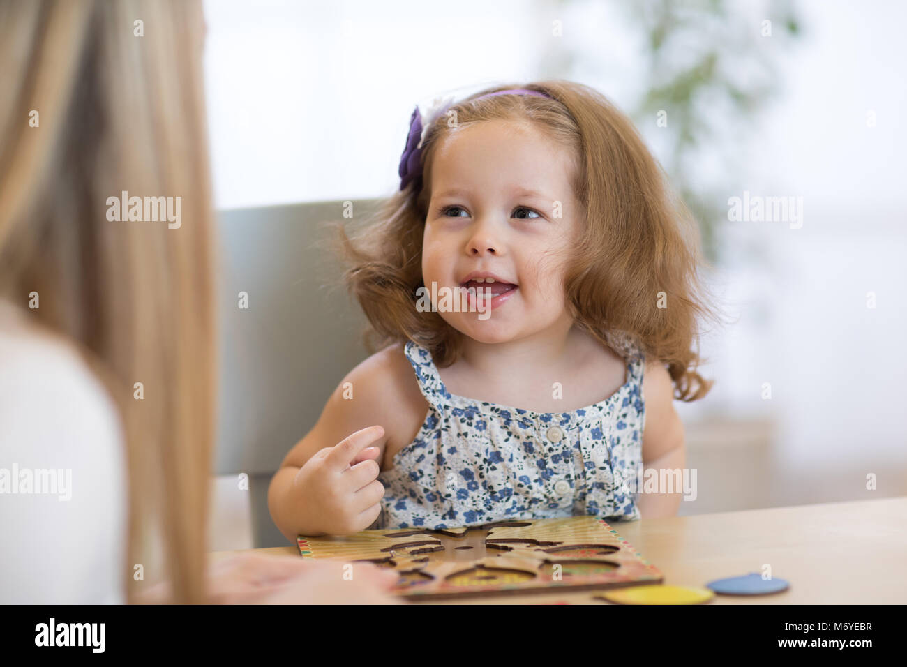 Child kid playing with puzzle shapes on table in children room in ...