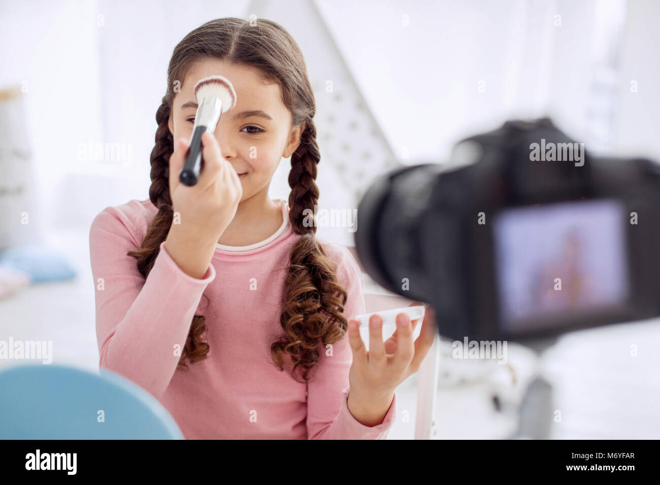Charming girl applying powder to forehead while filming vlog Stock ... Charming girl applying powder to forehead while filming vlog Stock ...